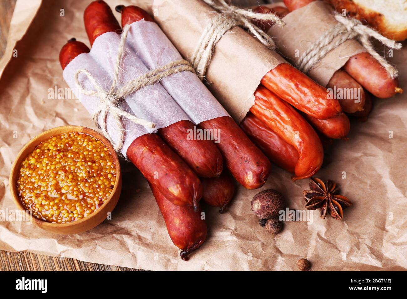Assortment of thin sausages, and spices on paper, on wooden background ...