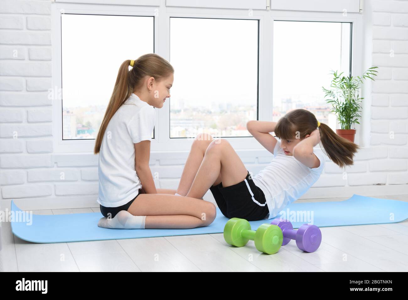 Older sister helps younger to do exercise for the press Stock Photo - Alamy