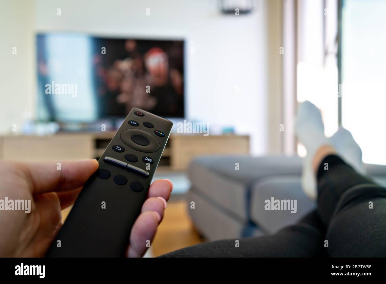 Watching TV, hand holding remote controller in front of big television ...