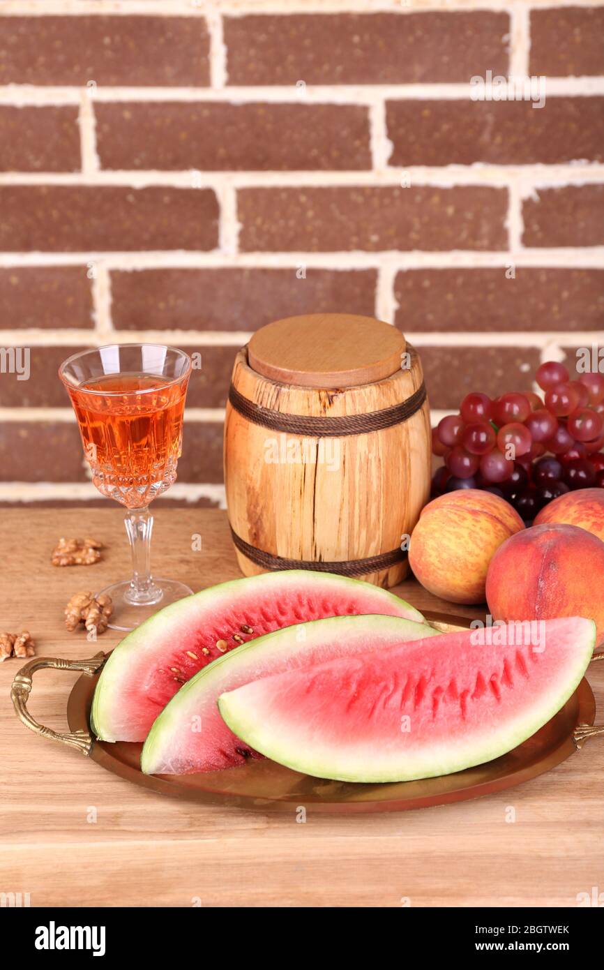 Composition of ripe watermelon, fruits, pink wine in glass and wooden ...