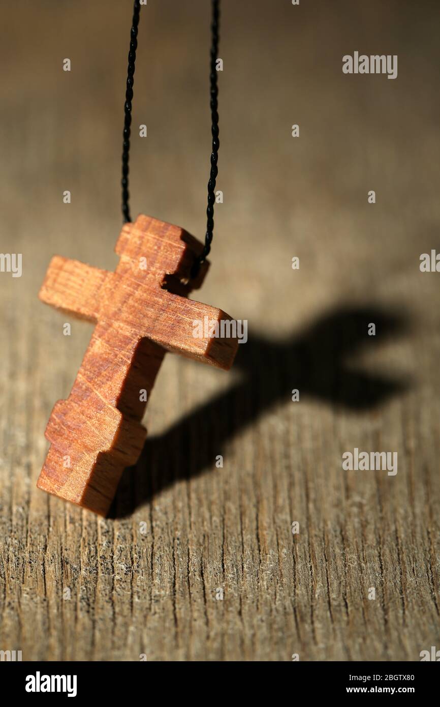 Wooden cross with deep shadow on wooden background Stock Photo - Alamy