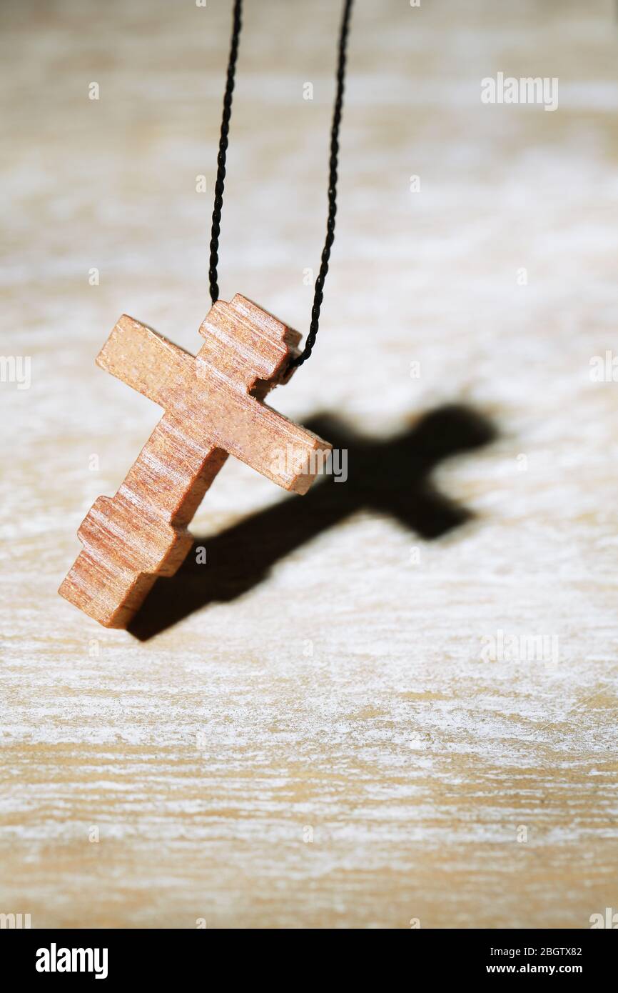 Wooden cross with deep shadow on wooden background Stock Photo - Alamy