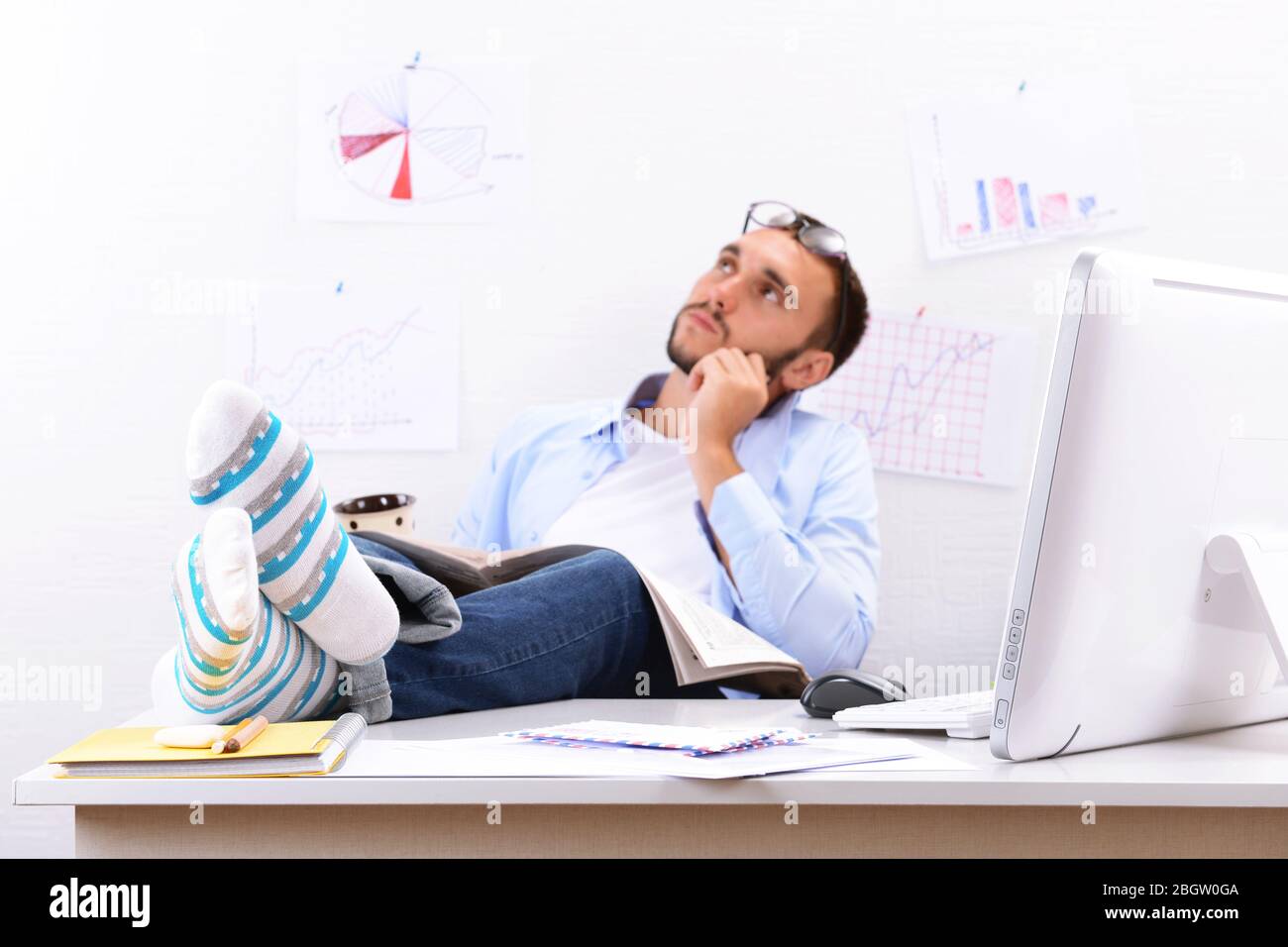 Confident businessman holding his legs in funny socks on desk Stock ...