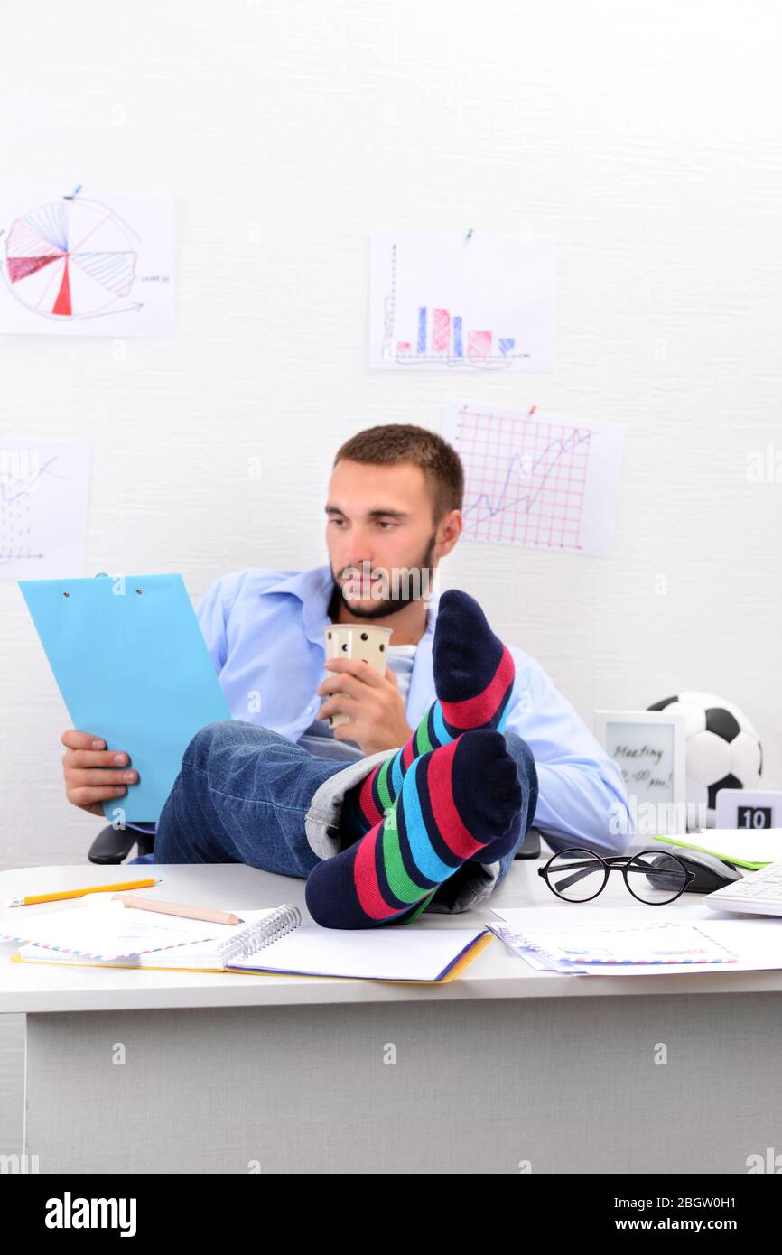 Confident businessman holding his legs in funny socks on desk Stock ...