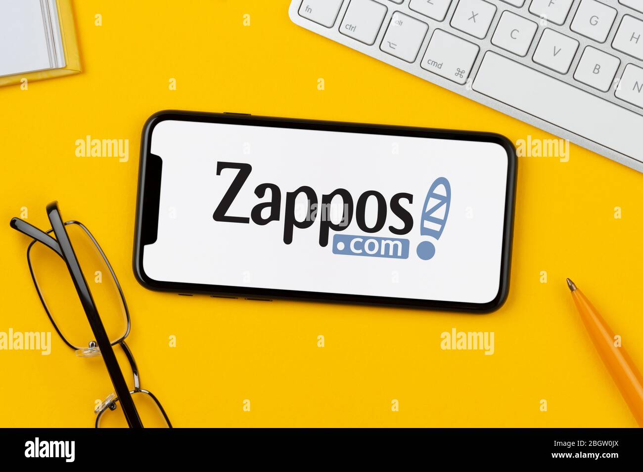 A smartphone showing the Zappos logo rests on a yellow background along ...