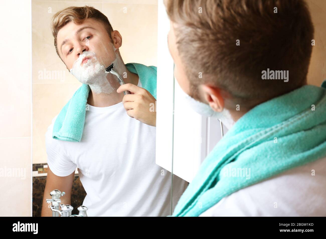 Young man shaving his beard in bathroom Stock Photo - Alamy