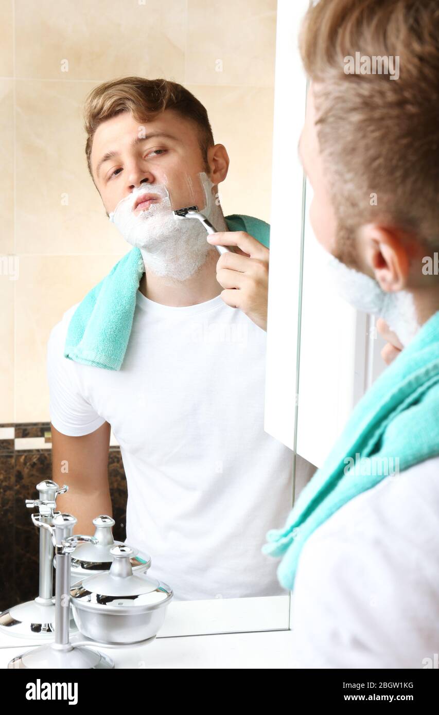 Young man shaving his beard in bathroom Stock Photo - Alamy