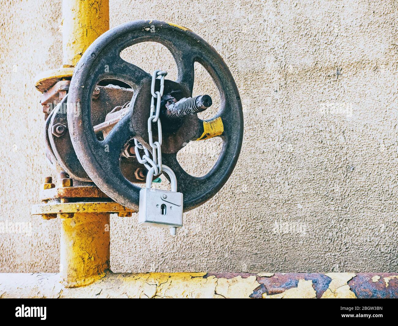 Round water valve with lock and chain on a yellow pipe Stock Photo - Alamy