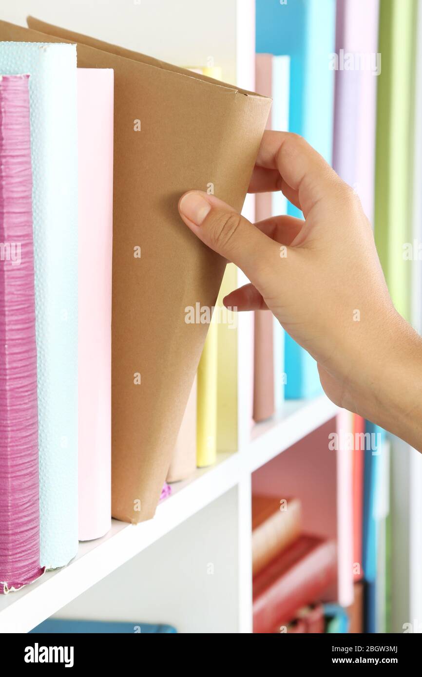 Hand picking book in library Stock Photo - Alamy