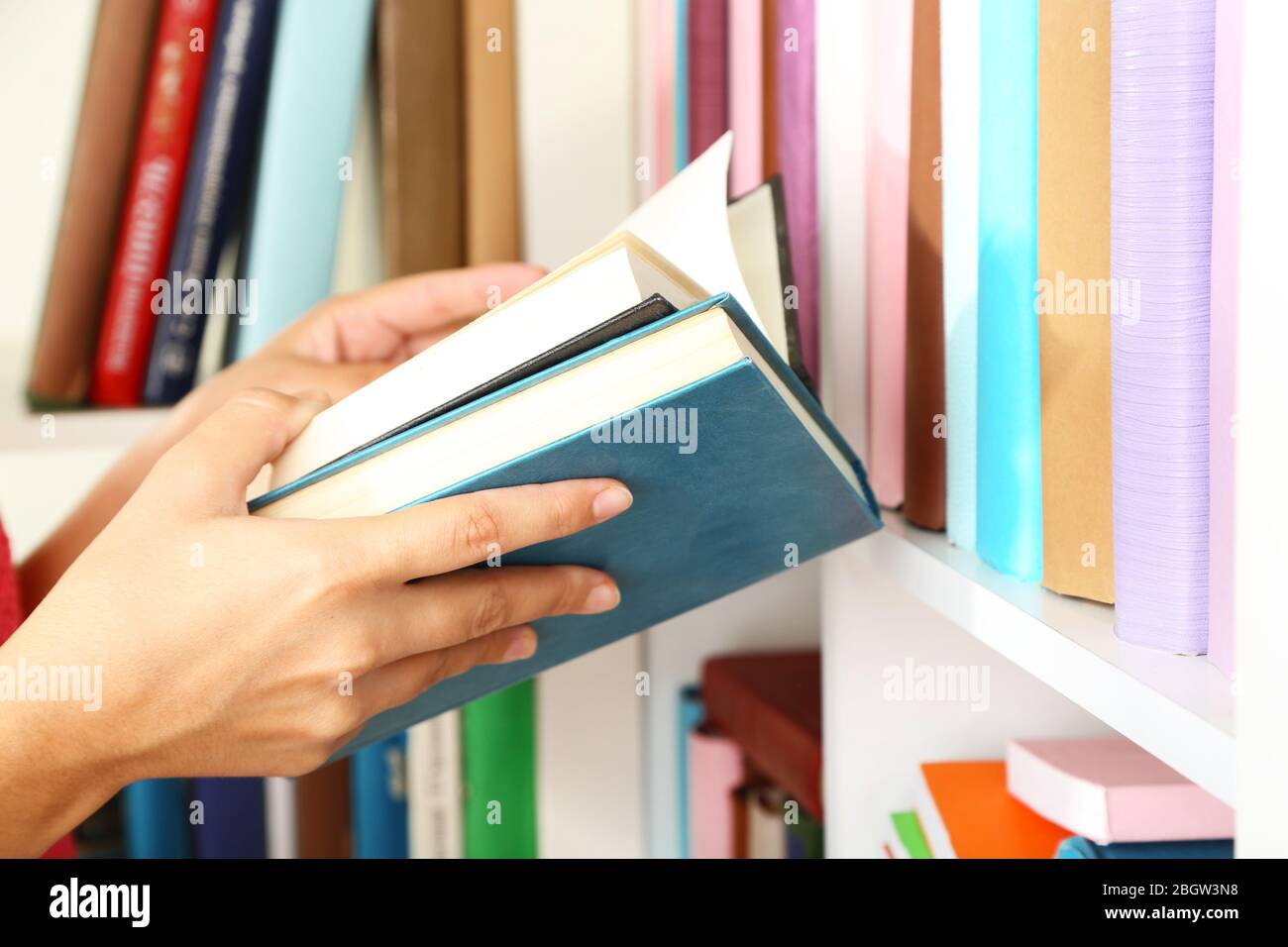 Hand picking book in library Stock Photo - Alamy
