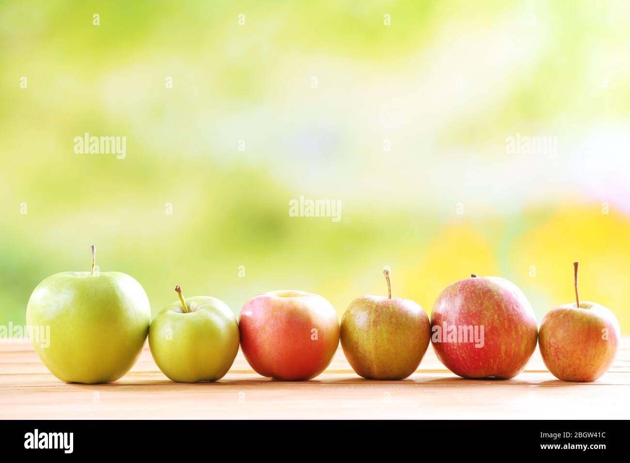 Juicy apples in row on table on bright background Stock Photo - Alamy