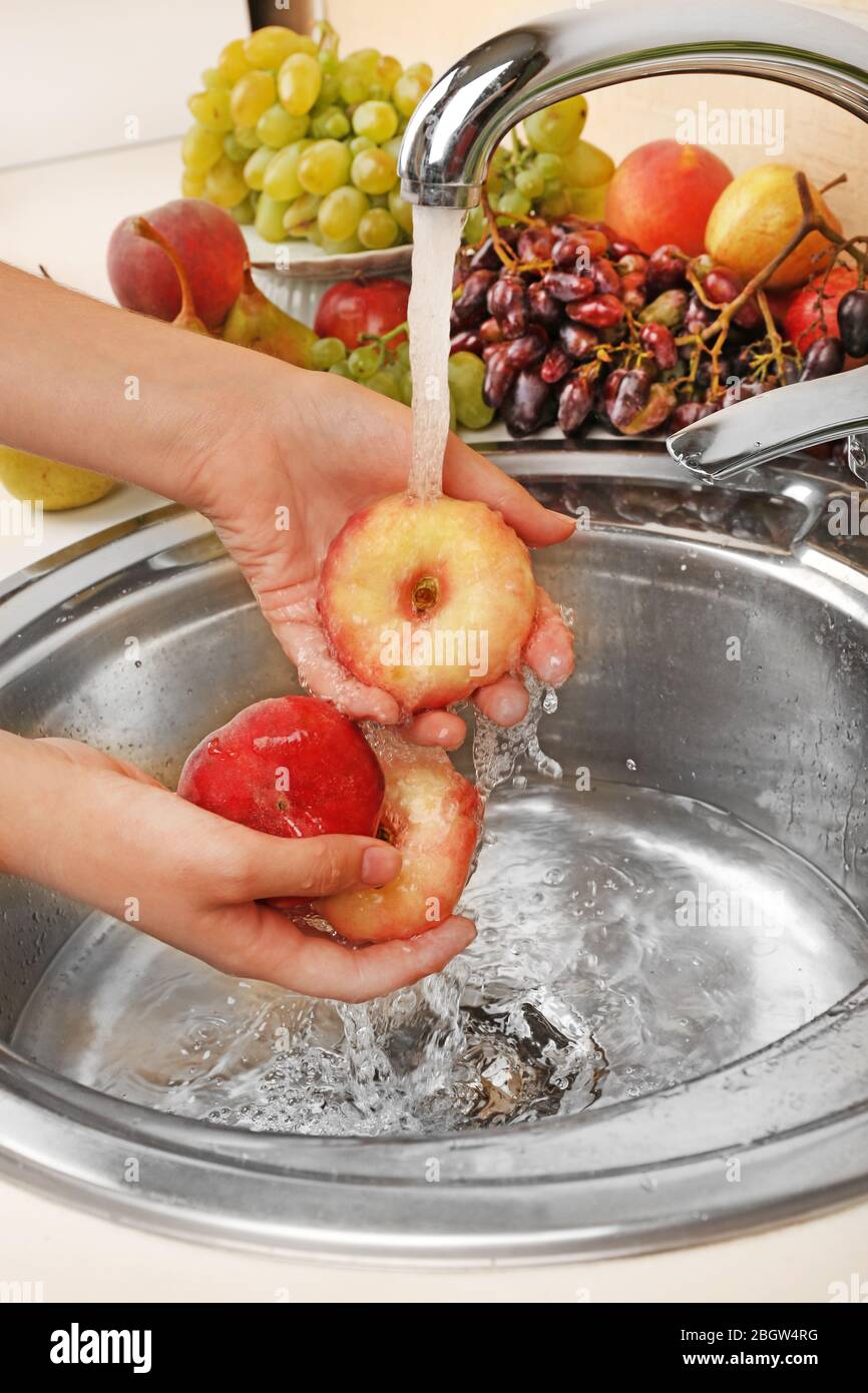 Woman's hands washing peaches in sink Stock Photo - Alamy