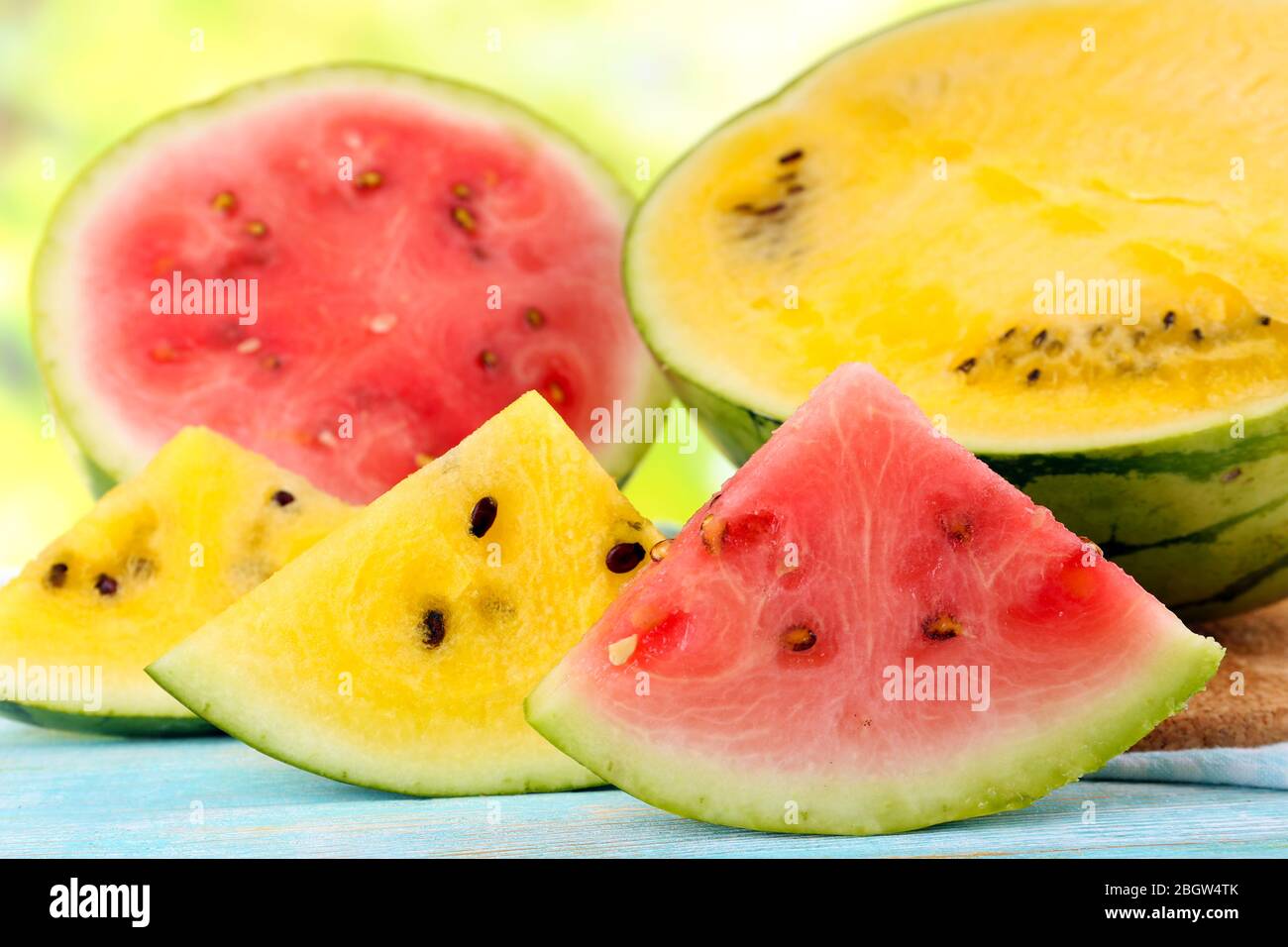 Slices of red and yellow watermelons on wooden table on natural ...
