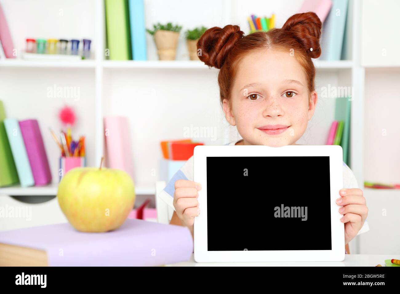 Cute girl with tablet at workplace in classroom Stock Photo - Alamy