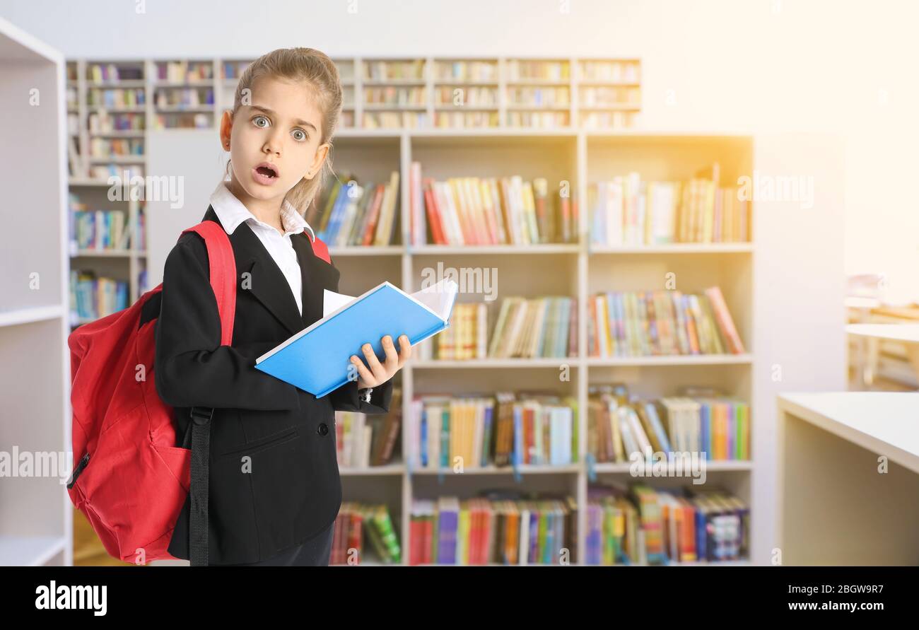 Shocked little schoolgirl in modern library Stock Photo - Alamy