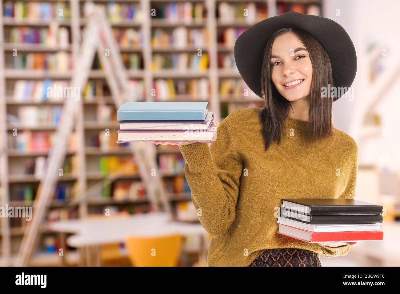 Beautiful young woman with books in modern library Stock Photo - Alamy