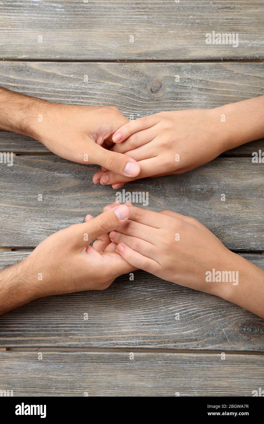 Loving couple holding hands close-up on wooden background Stock Photo ...