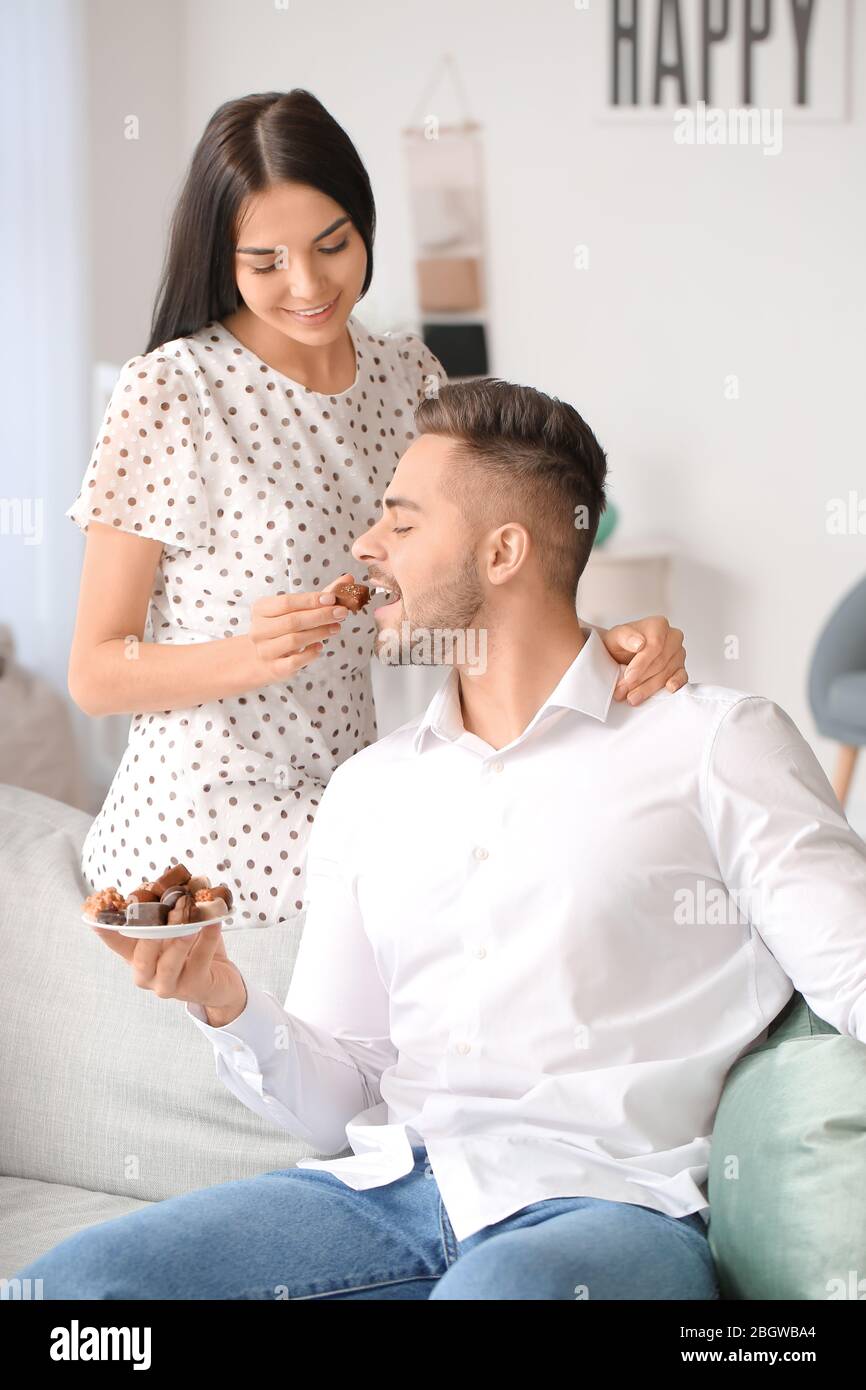 Beautiful young couple eating chocolate at home Stock Photo - Alamy