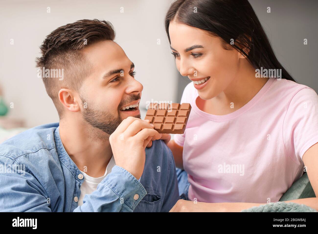 Beautiful young couple eating chocolate at home Stock Photo - Alamy