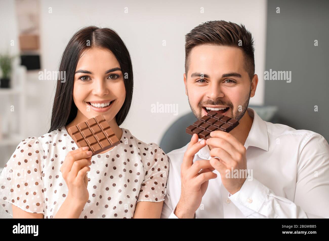 Beautiful young couple eating chocolate at home Stock Photo - Alamy