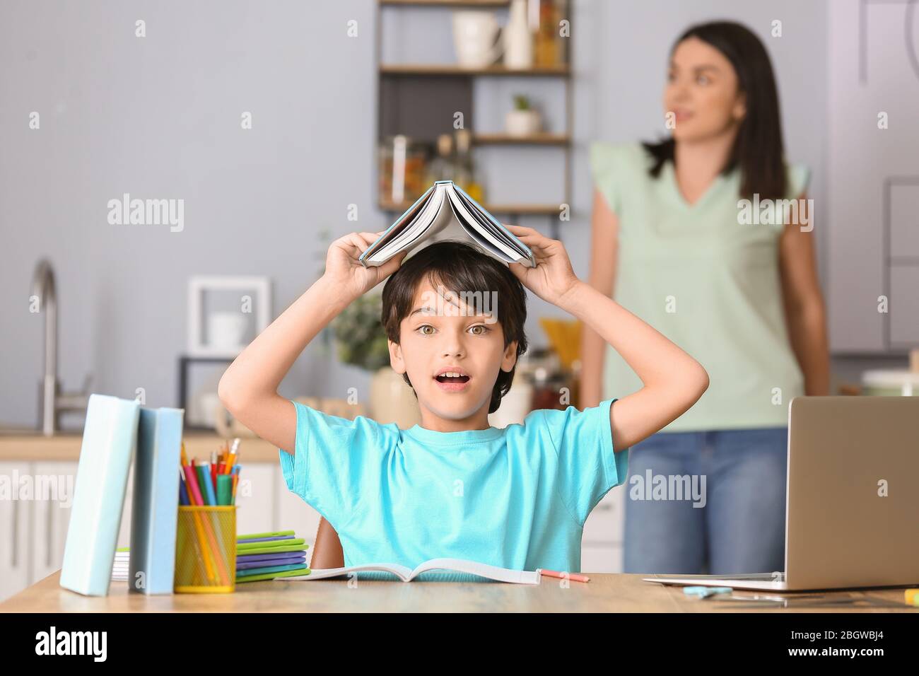 Troubled little boy doing homework in kitchen Stock Photo - Alamy