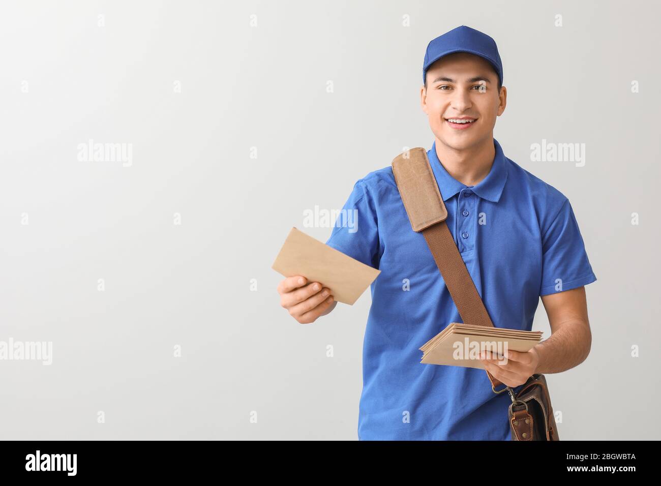 Postman with letters on light background Stock Photo - Alamy