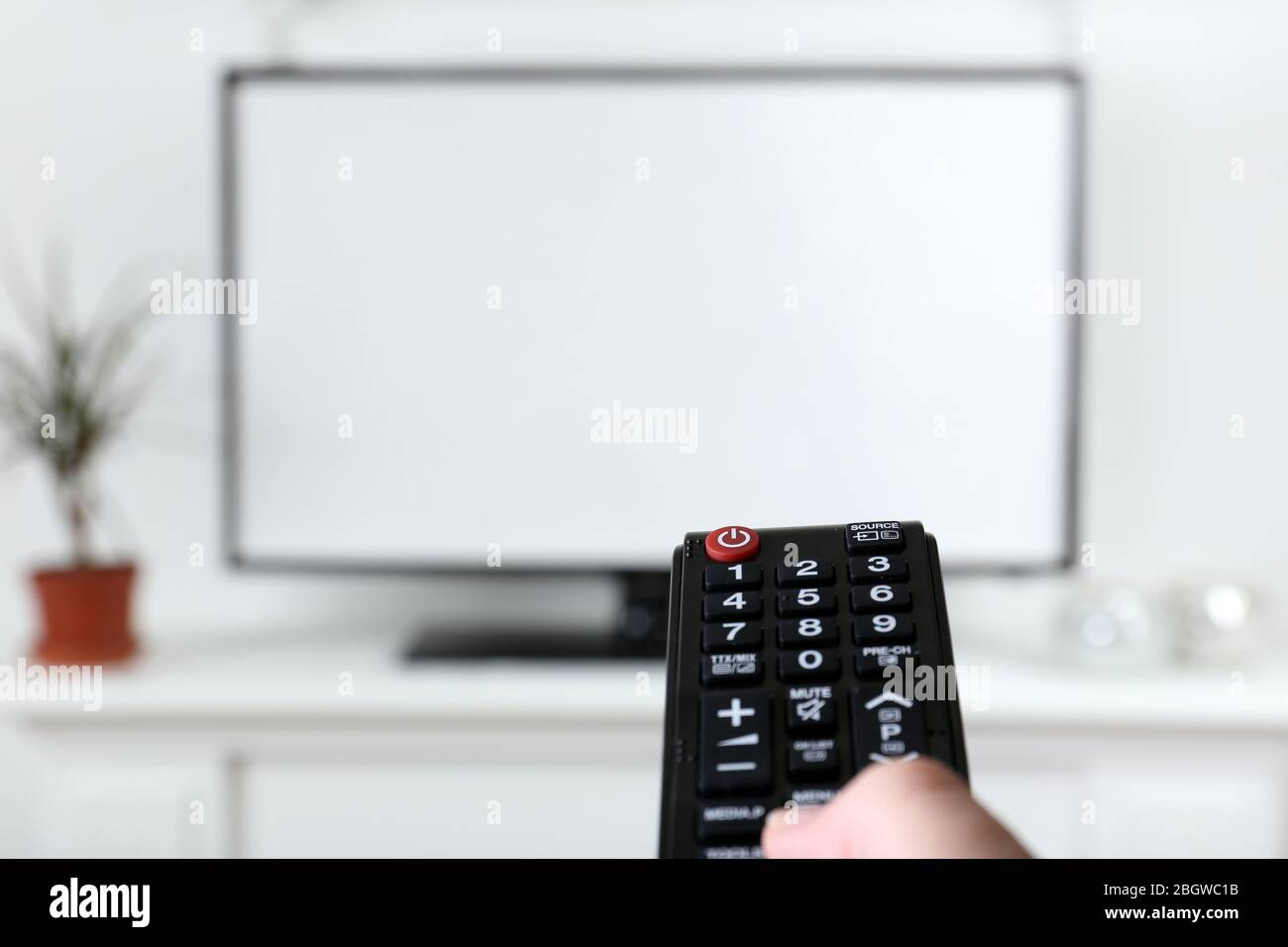 Watching TV and using remote controller Stock Photo - Alamy