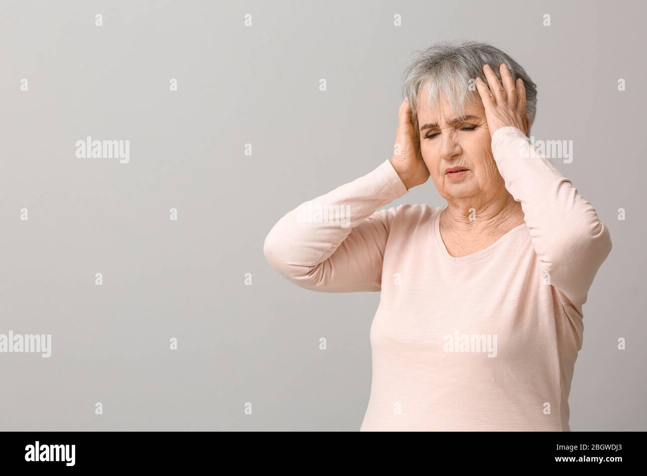 Elderly woman suffering from mental disability on grey background Stock ...