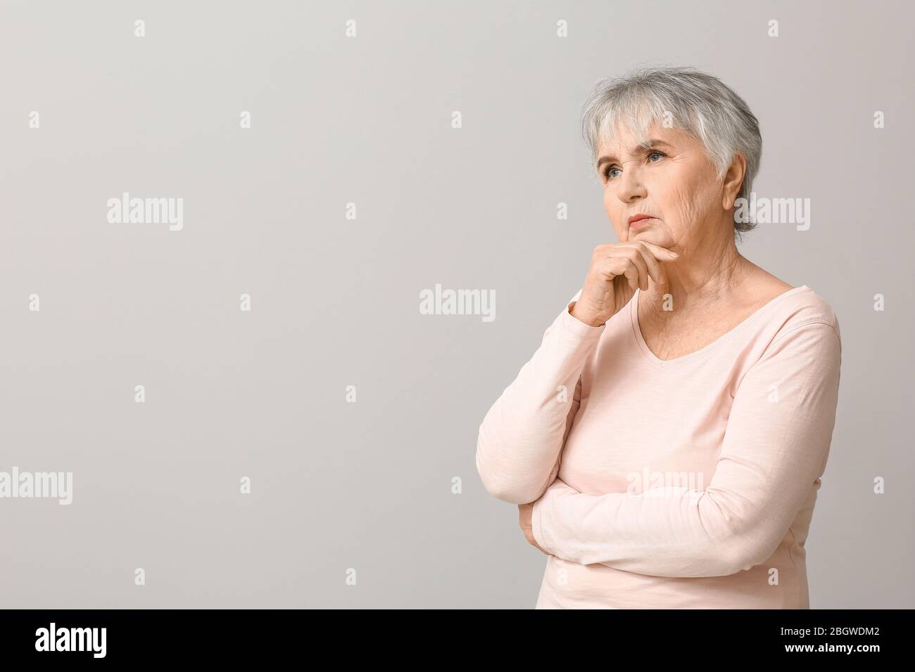 Elderly woman suffering from mental disability on grey background Stock ...