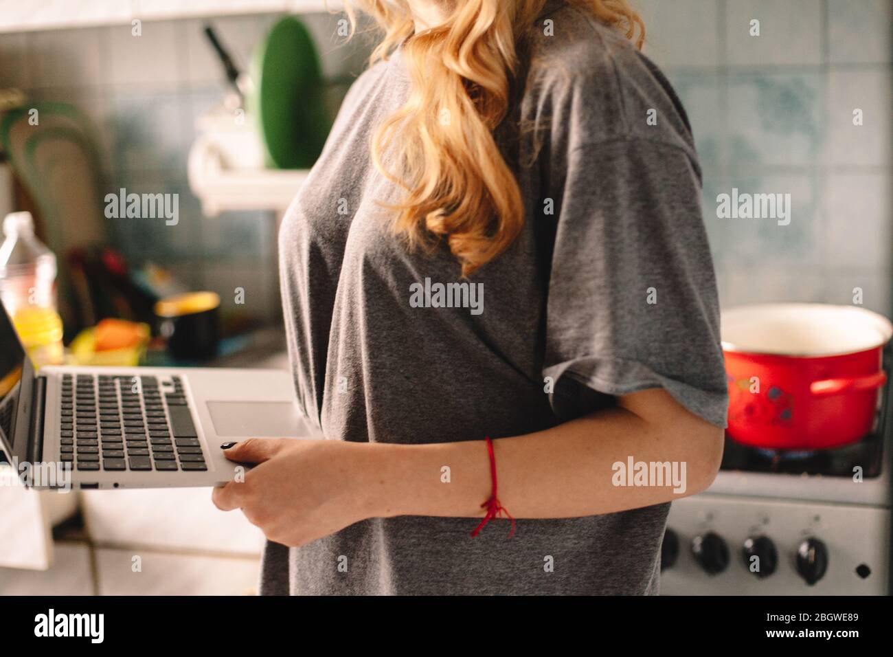 Woman using laptop computer while cooking food on kitchen Stock Photo ...