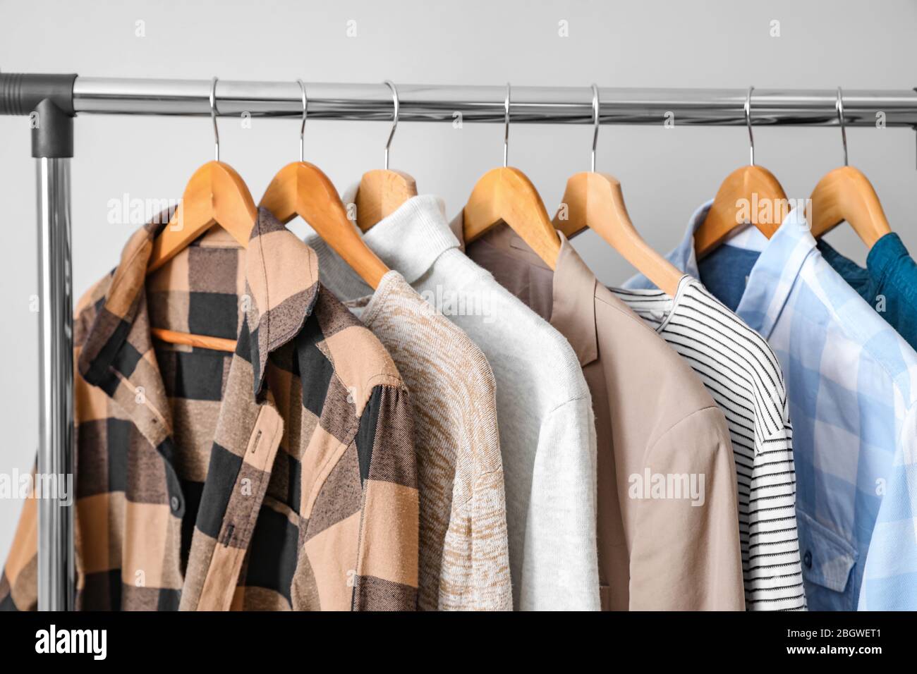 Rack with clothes on light background Stock Photo - Alamy