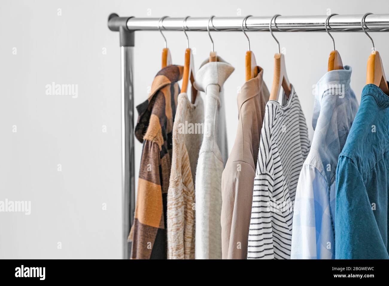 Rack with clothes on light background Stock Photo - Alamy