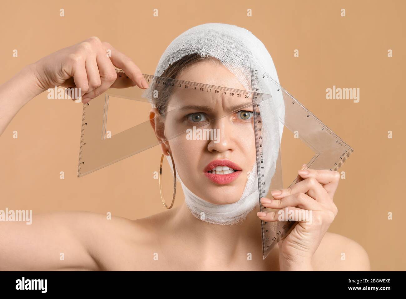 Young woman with bandage on head and rulers on color background ...
