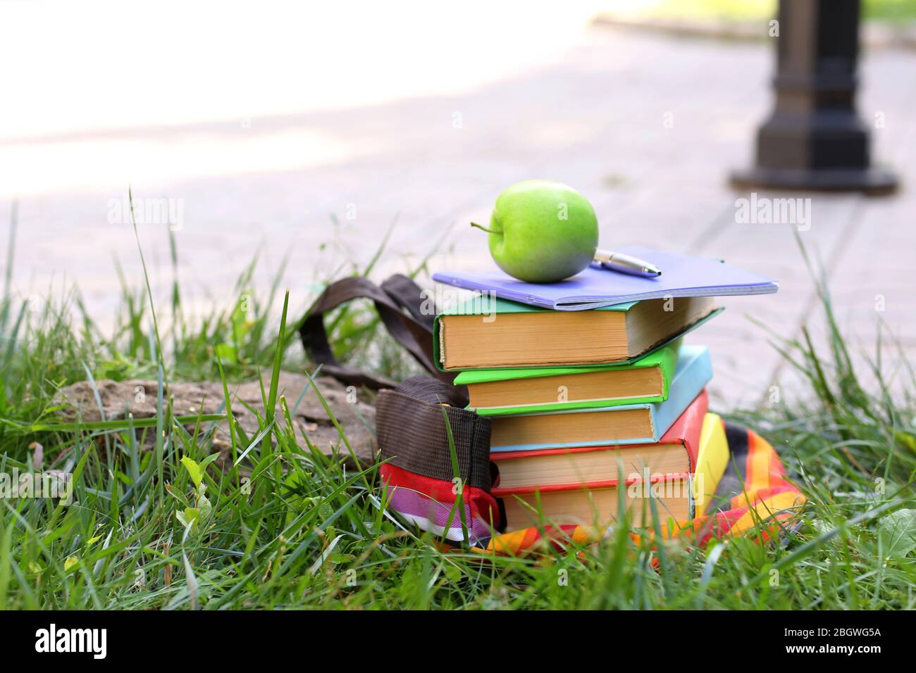 Stacked books in grass, outside Stock Photo - Alamy