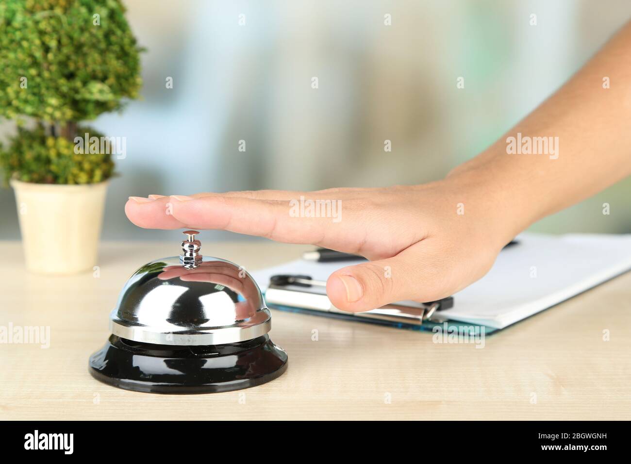 Female hand ring bell on hotel reception desk, on bright background ...