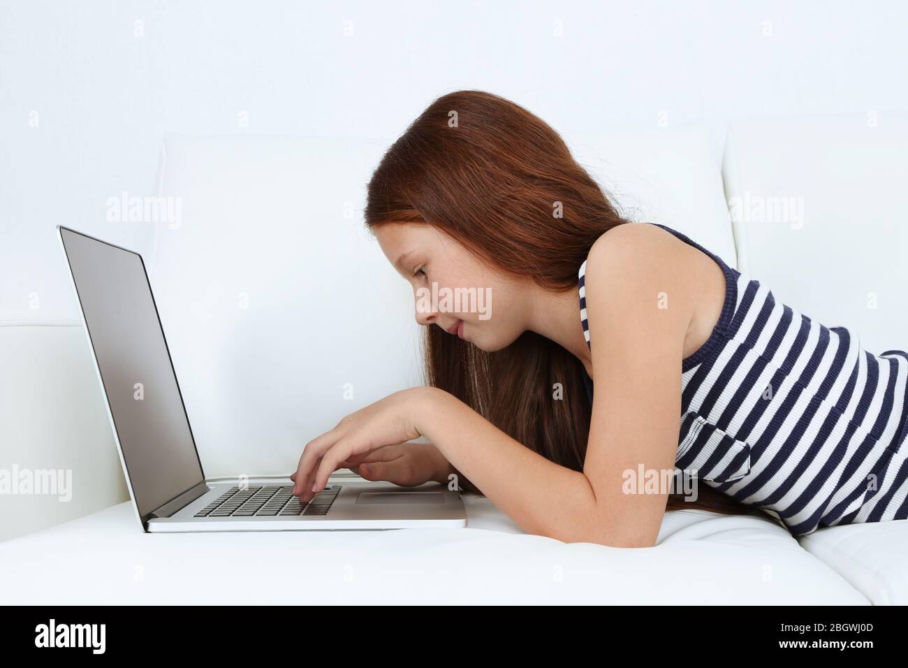 Beautiful little girl with laptop on sofa in room Stock Photo - Alamy