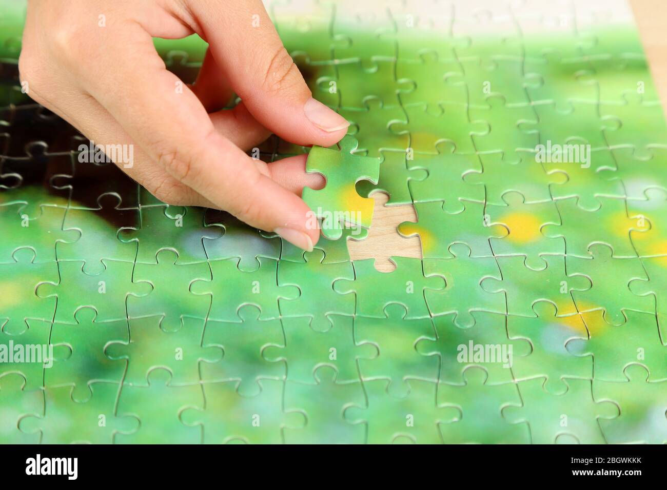Hand holding puzzle piece on wooden table background Stock Photo - Alamy