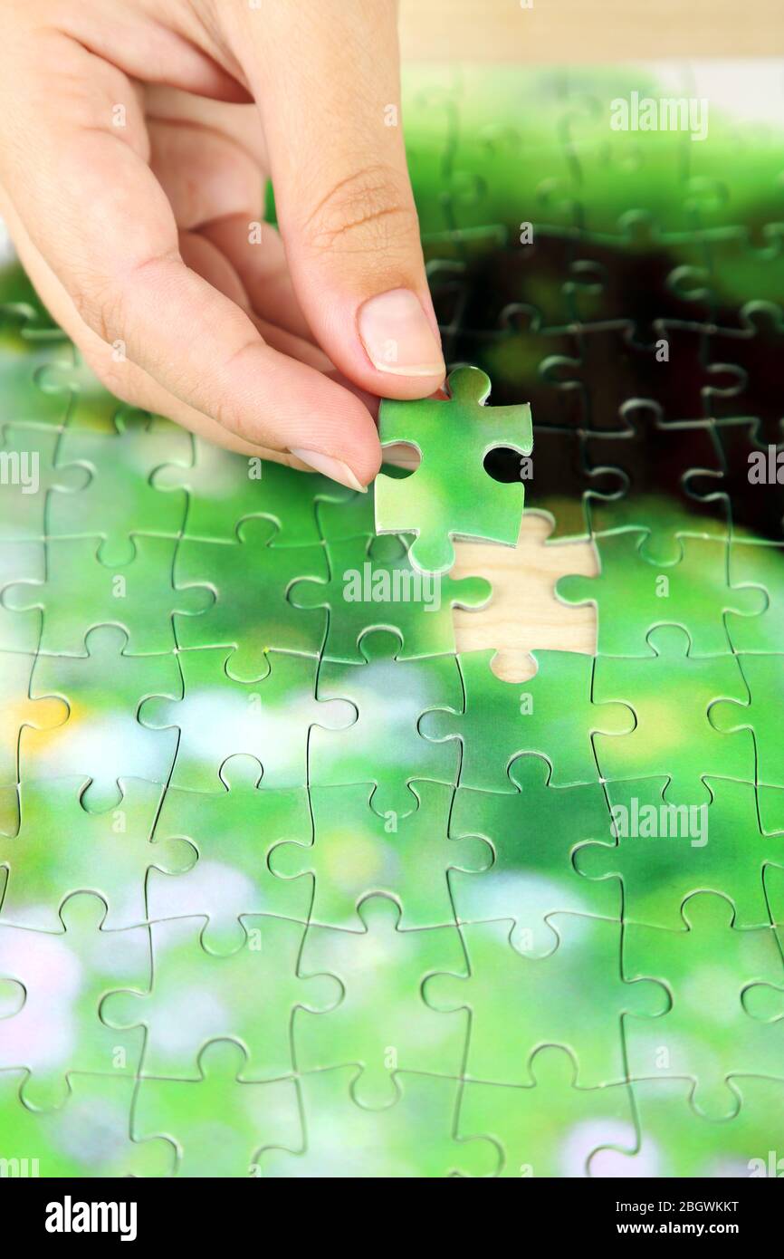 Hand holding puzzle piece on wooden table background Stock Photo - Alamy