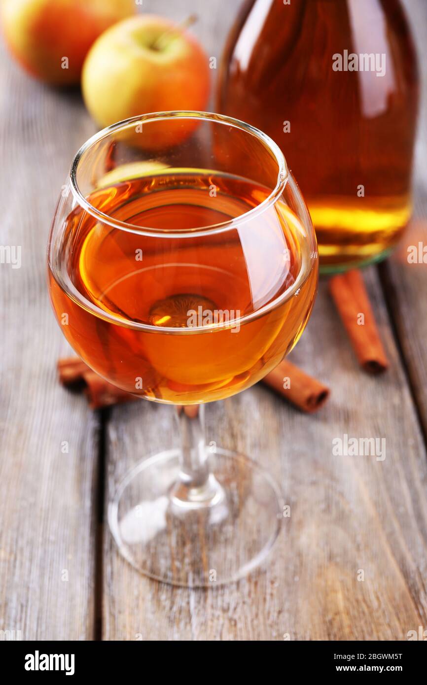 Apple cider in wine glass and bottle, with cinnamon sticks and fresh ...
