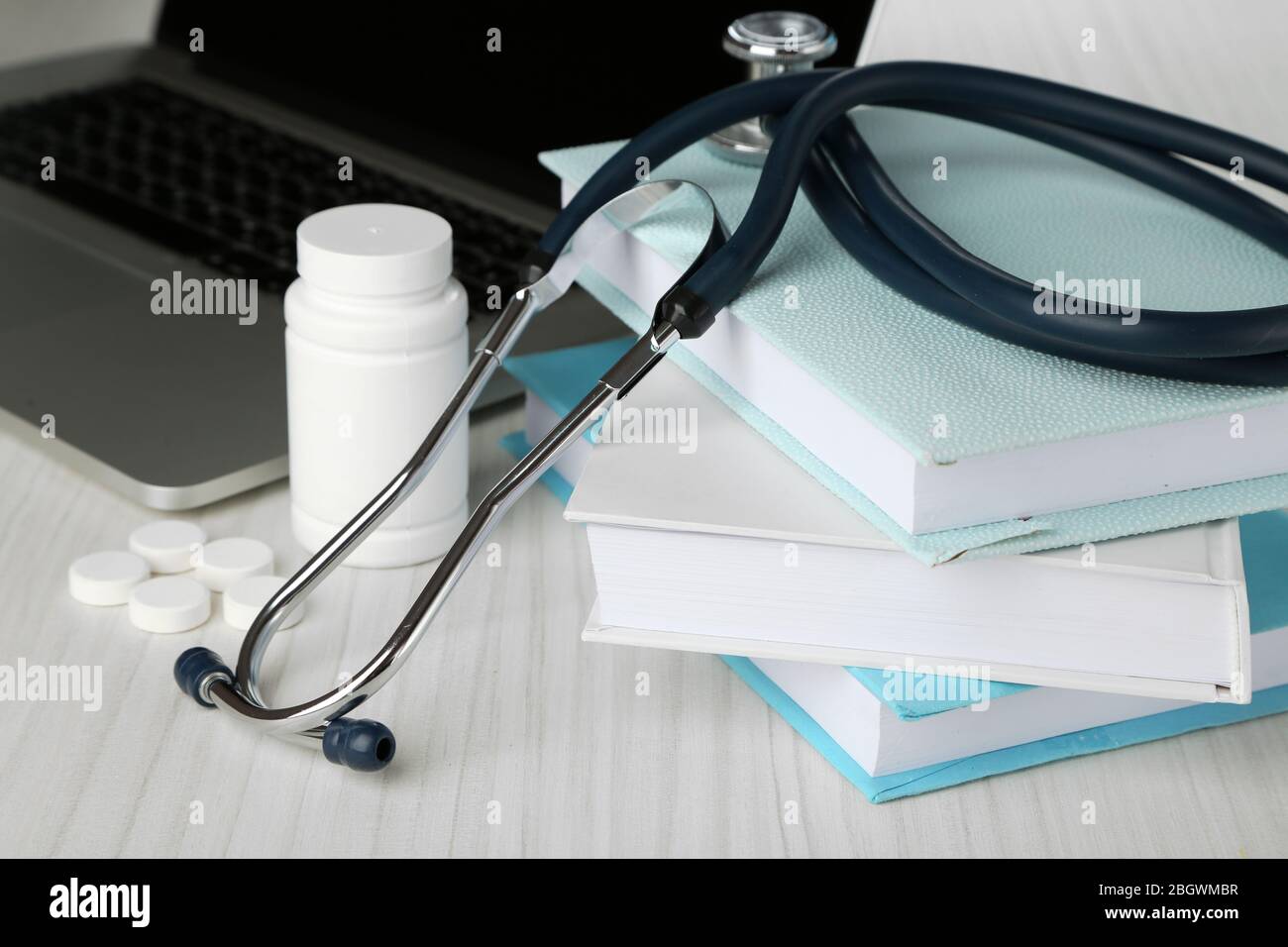 Medical stethoscope with books and laptop on wooden table Stock Photo ...