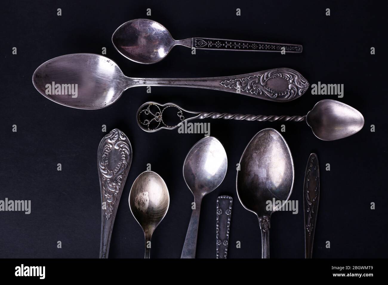 Metal spoons on black background Stock Photo - Alamy