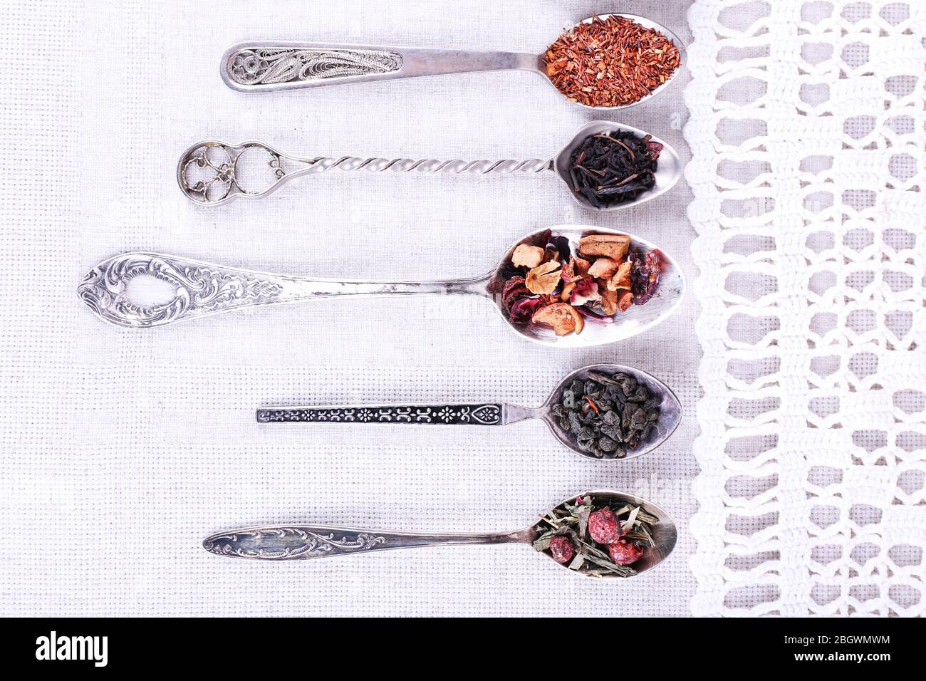 Tea in metal spoons on lace fabric background Stock Photo - Alamy