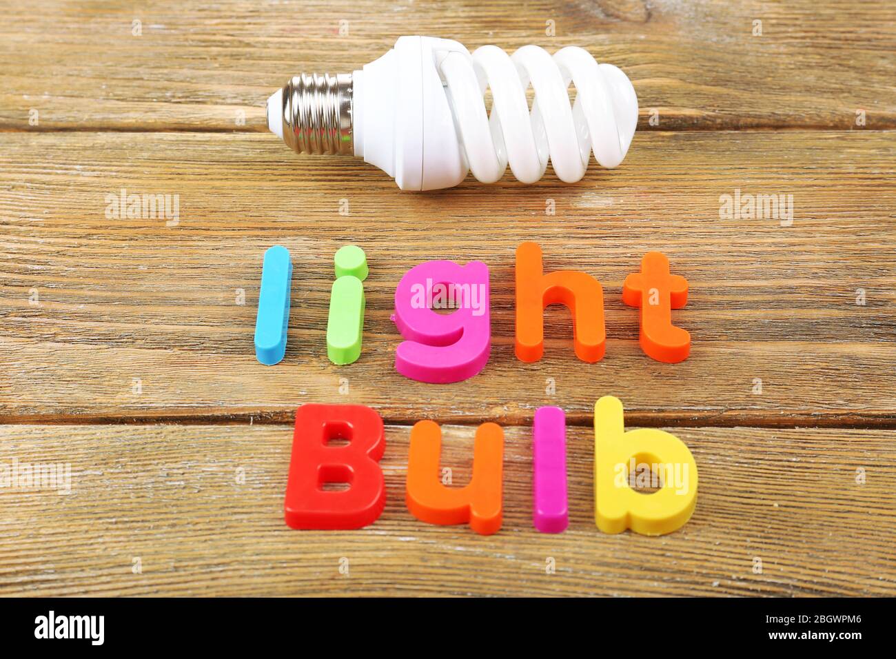 Light bulb word formed with colorful letters on wooden background Stock ...