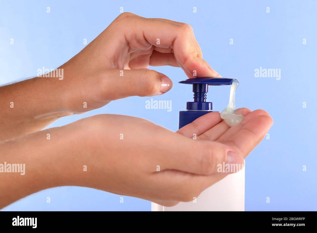 Female hands using liquid soap on light blue background Stock Photo - Alamy