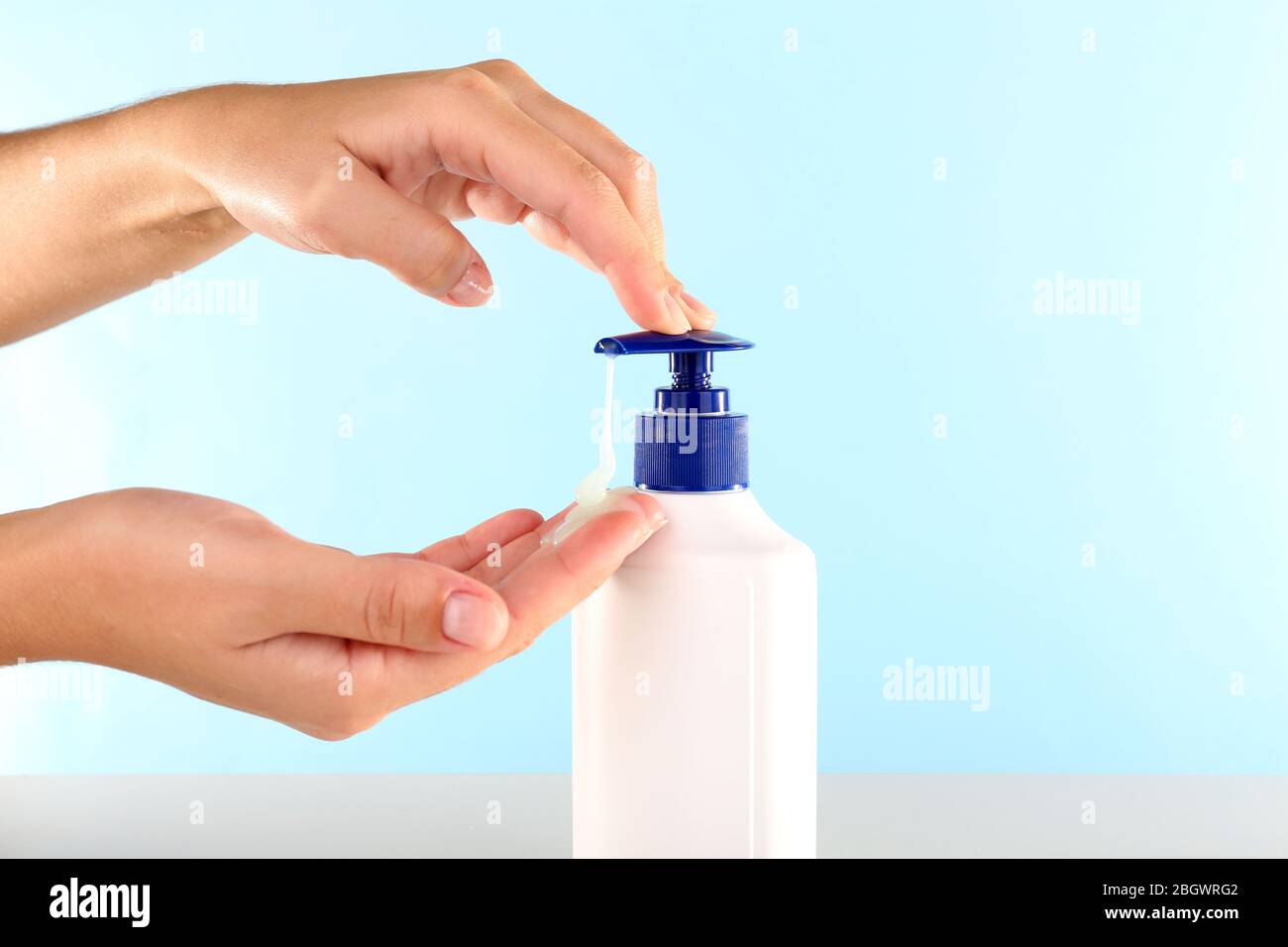 Female hands using liquid soap on light blue background Stock Photo - Alamy