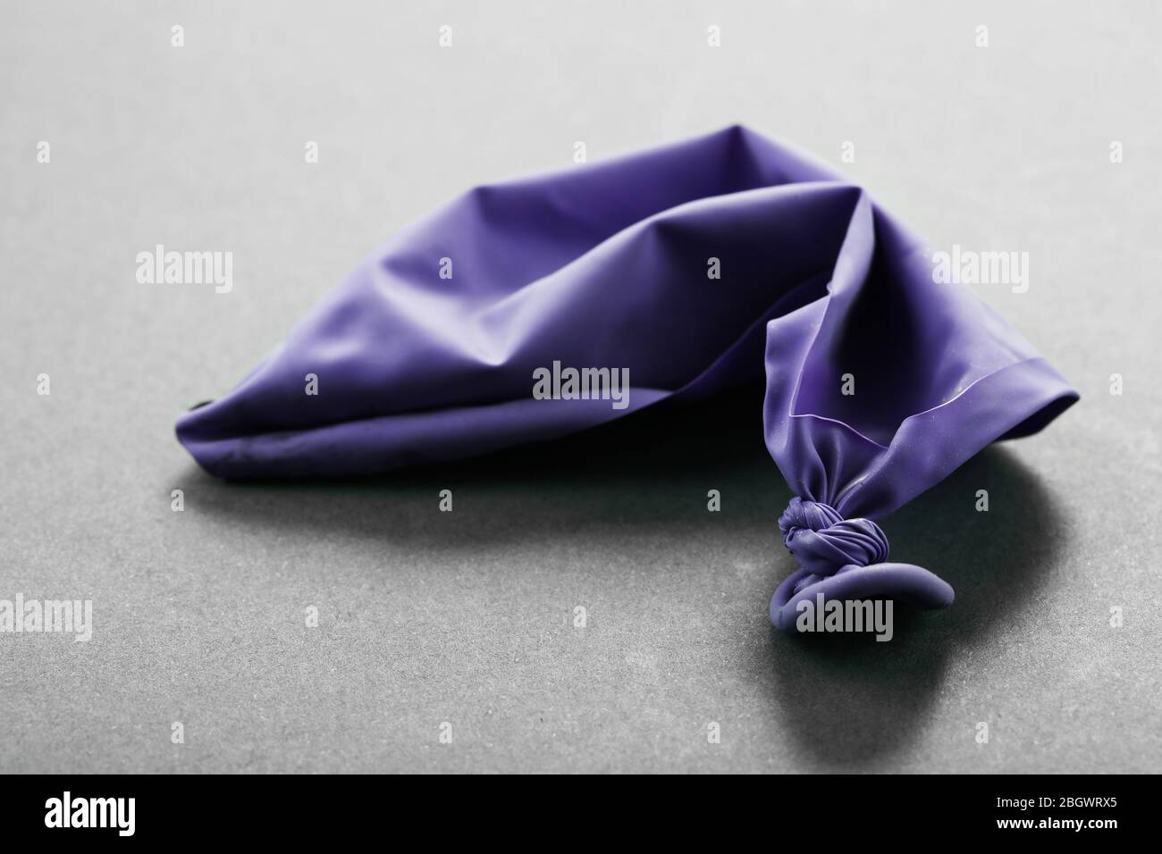 Popped violet balloon on paper background Stock Photo - Alamy