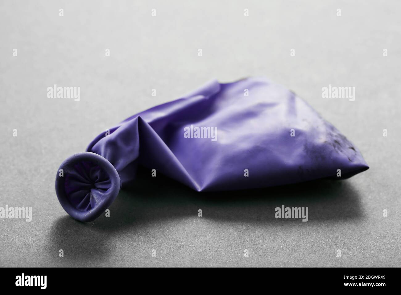 Popped violet balloon on paper background Stock Photo - Alamy