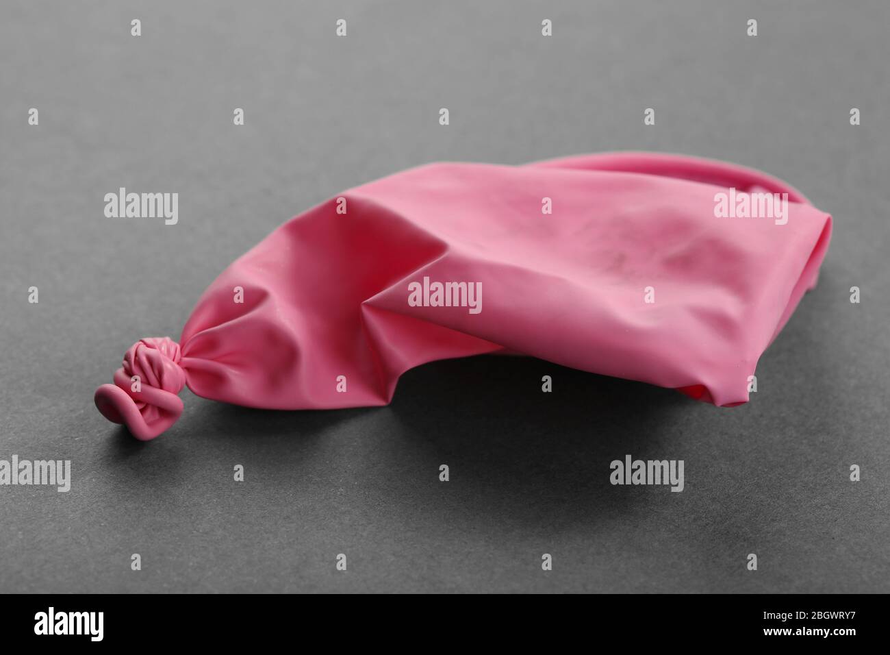 Popped pink balloon on paper background Stock Photo - Alamy