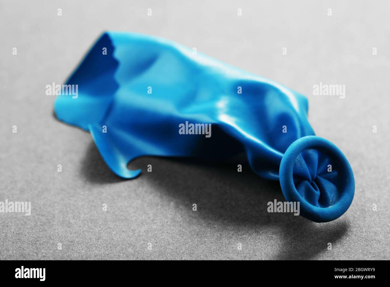 Popped blue balloon on paper background Stock Photo - Alamy