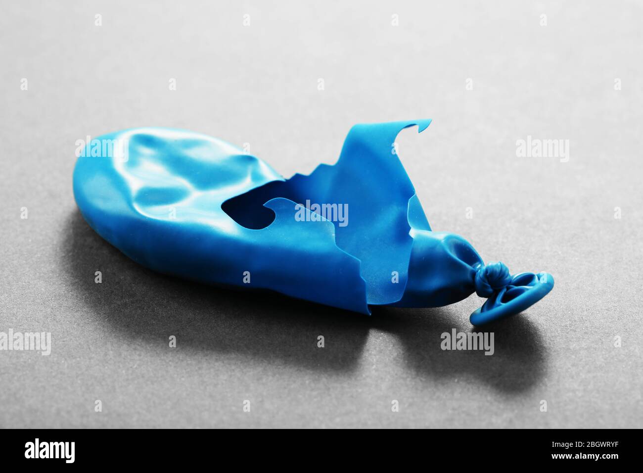 Popped blue balloon on paper background Stock Photo - Alamy